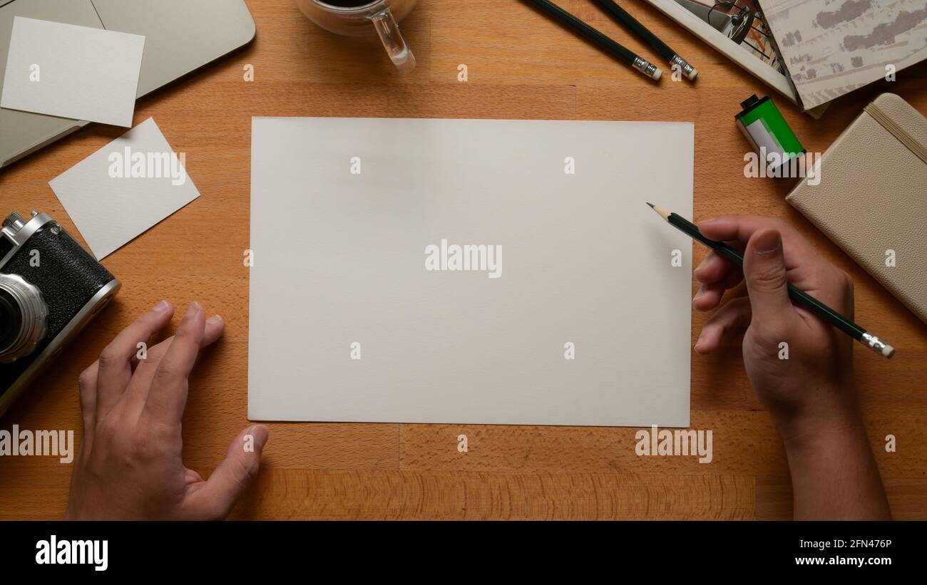 Top view of male artist working with blank sketch paper, pencils ...