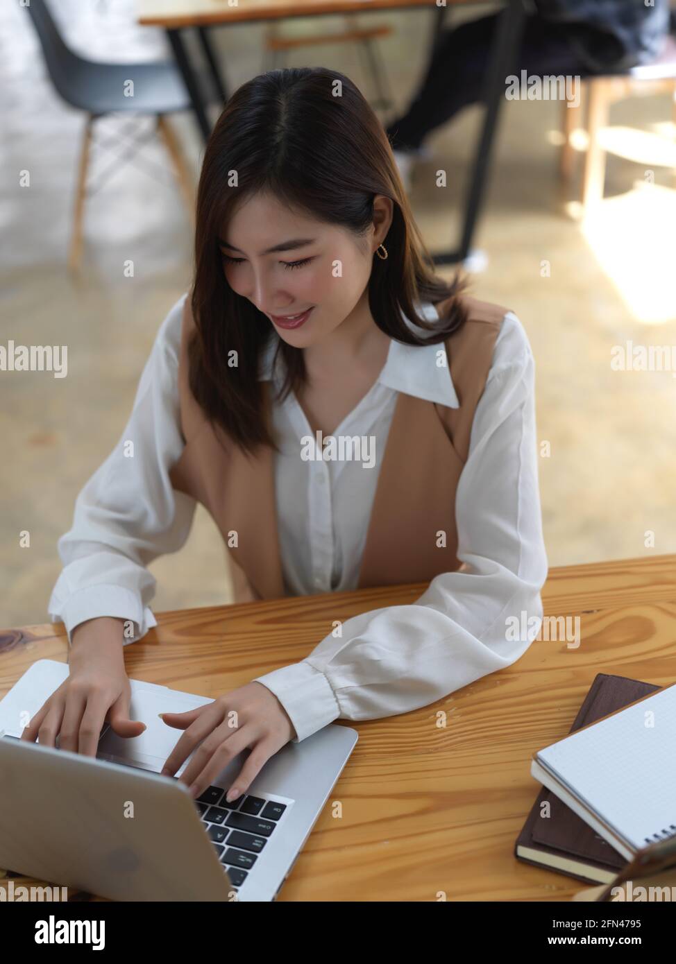 Overhead shot of female college student doing homework with laptop and ...