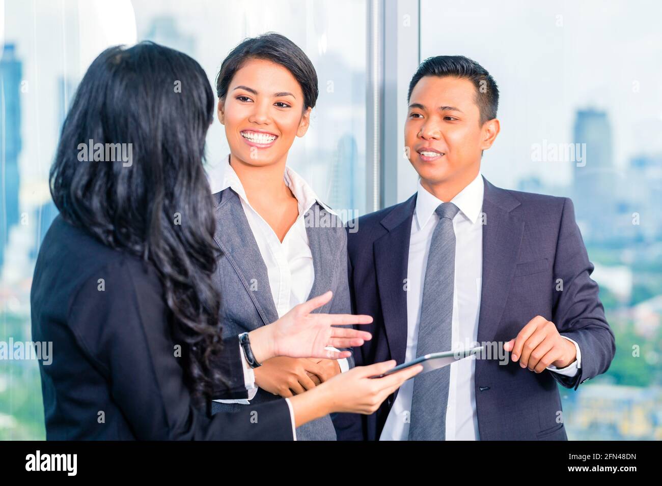 Asian Businesspeople standing in office talking Stock Photo - Alamy