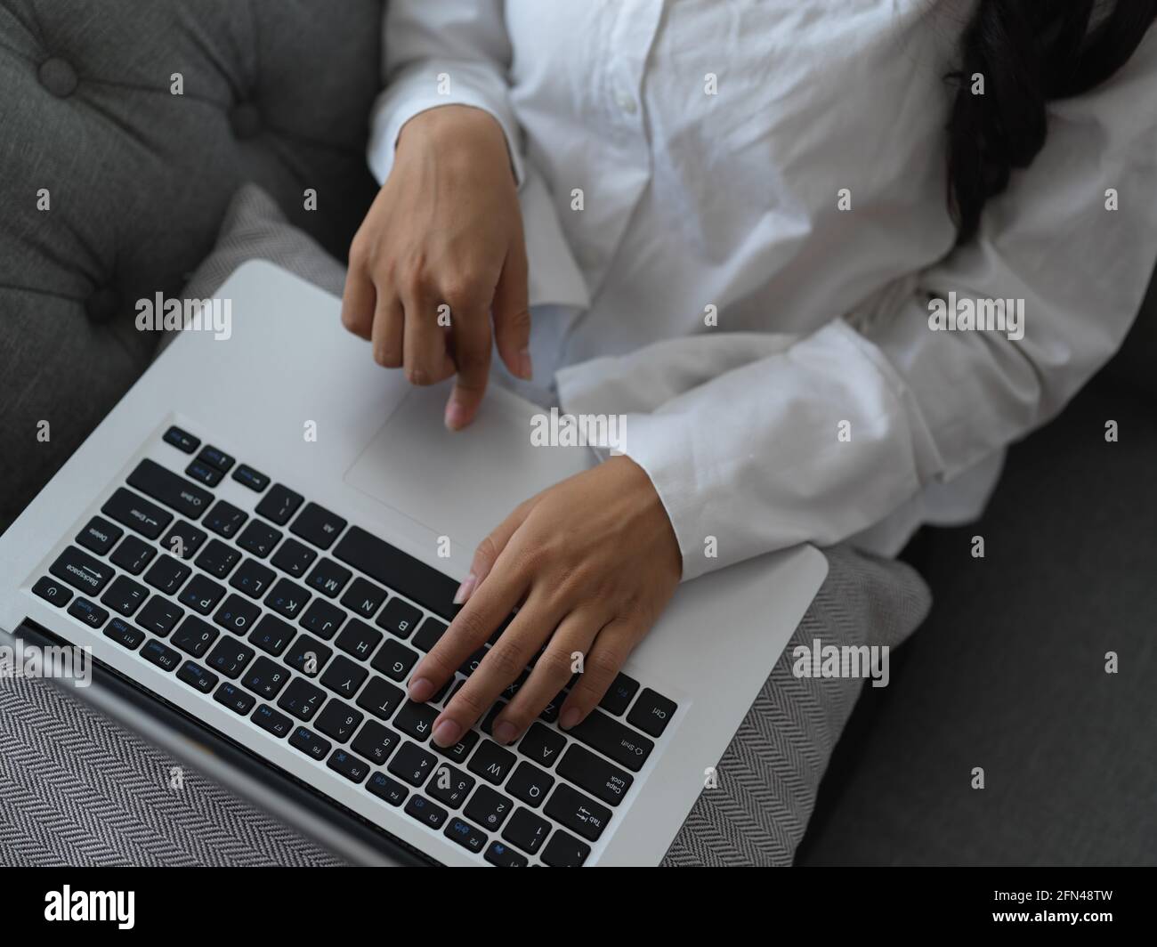 Overhead shot of female hands typing on laptop keyboard on her lap ...