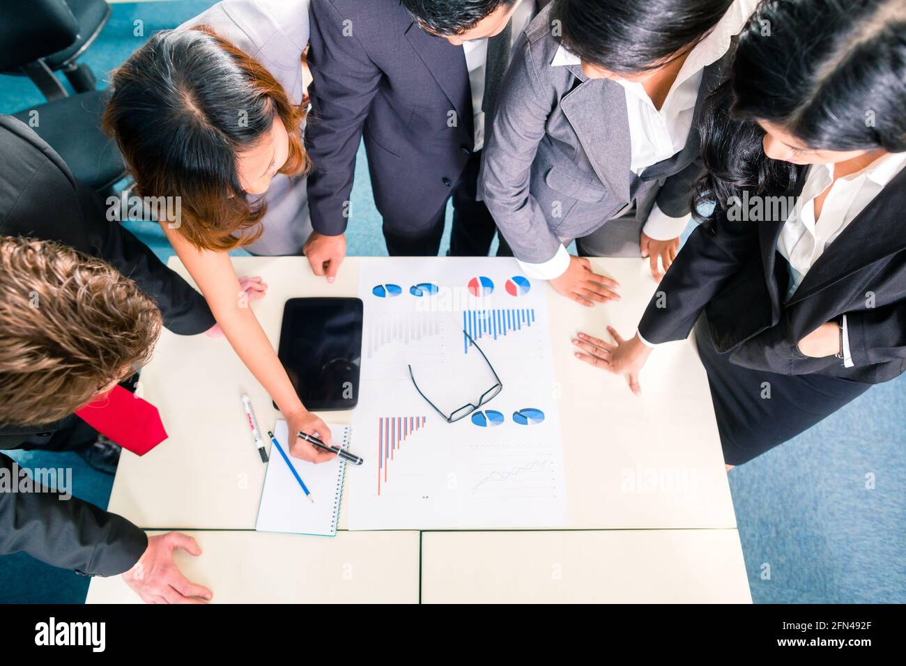 Overhead view of Asian businesspeople anaylzing graph Stock Photo - Alamy
