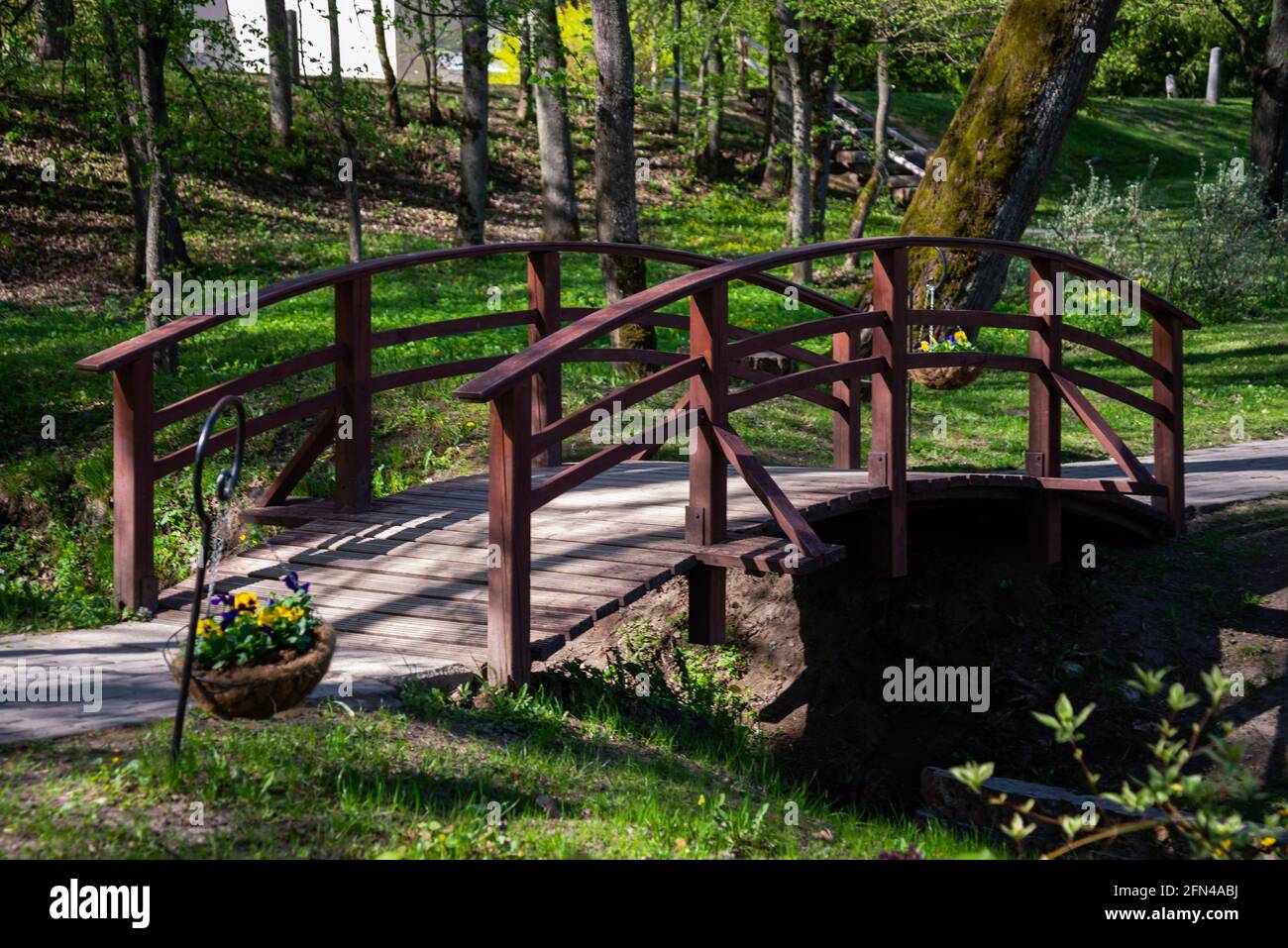 red wooden bridge for pedestrians over a small park river. Widow's ...