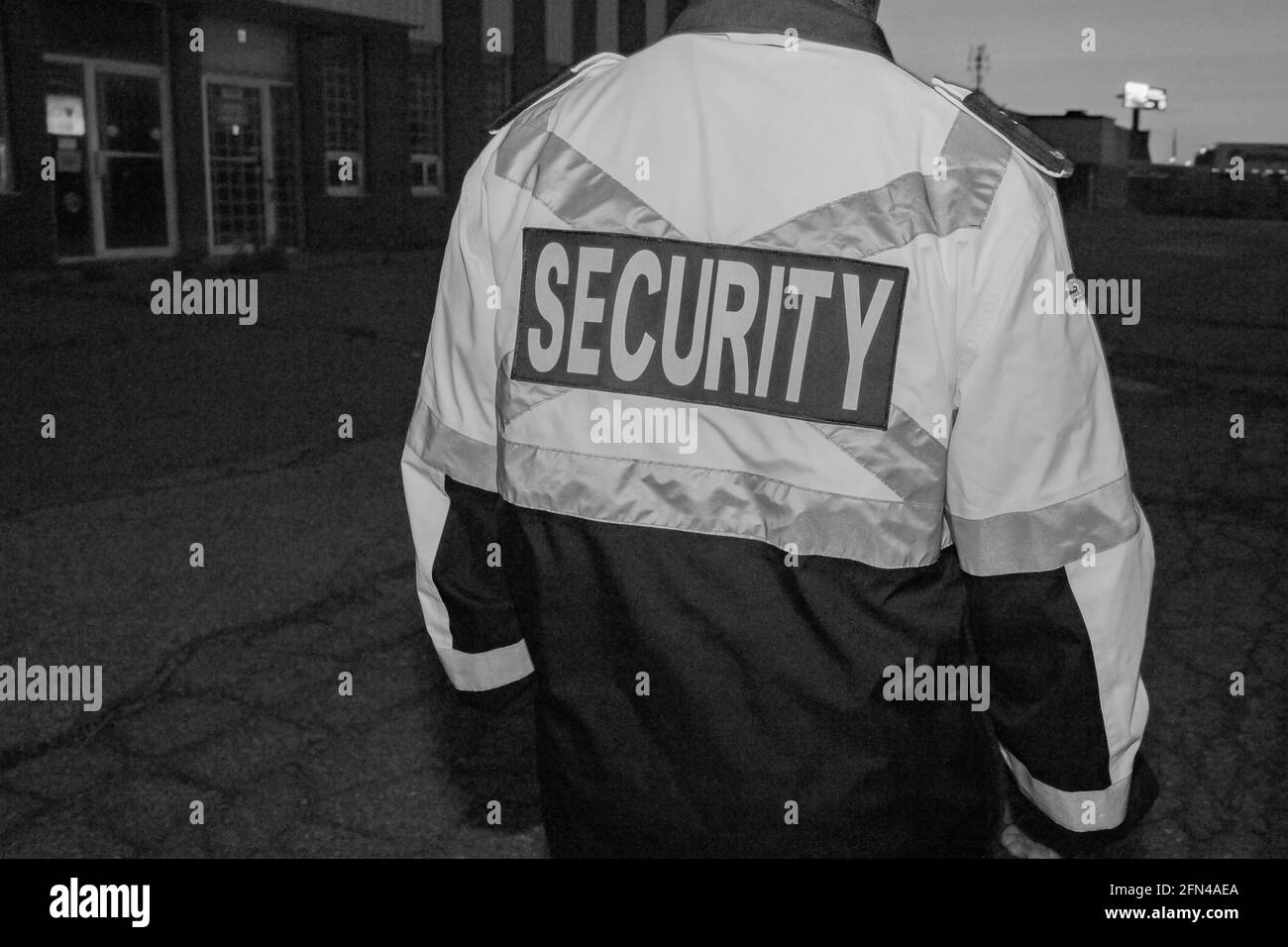 A rear view of a security guard looking down the street and sunset ...