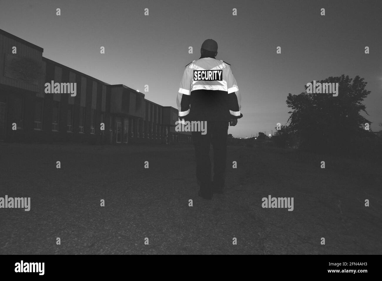 A rear view of a security guard looking down the street and sunset ...