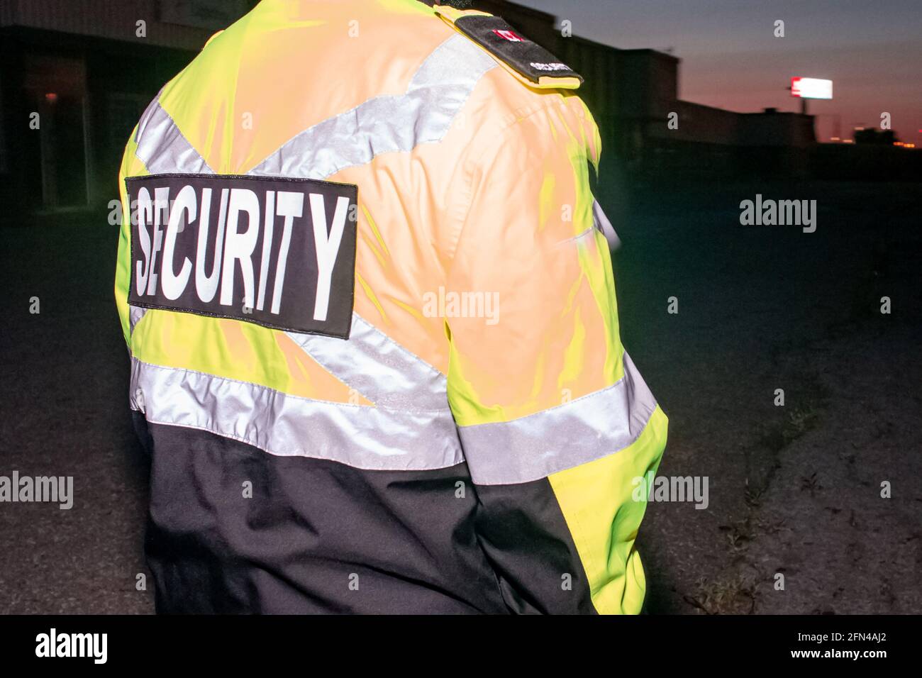 A rear view of a security guard looking down the street and sunset ...