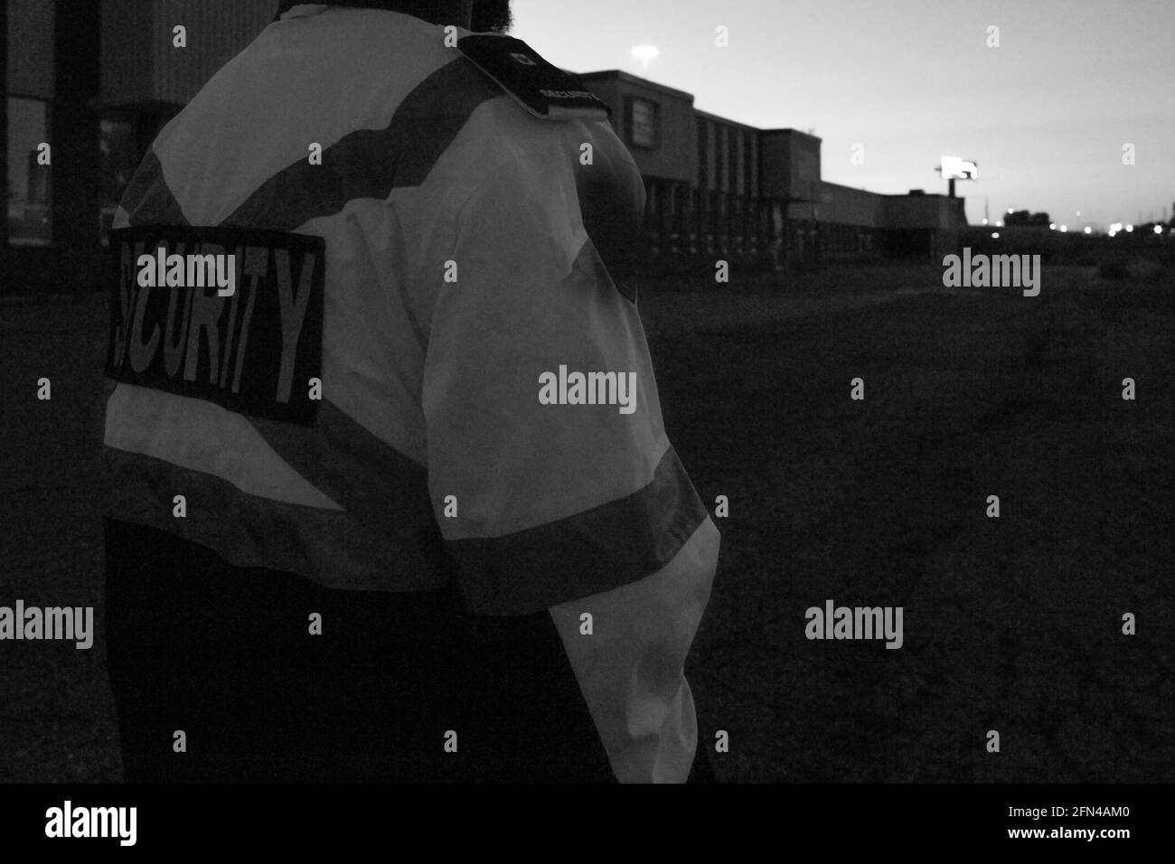 A rear view of a security guard looking down the street and sunset ...