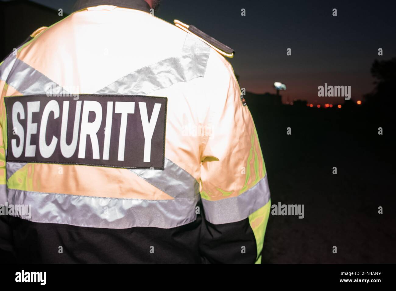 A rear view of a security guard looking down the street and sunset ...