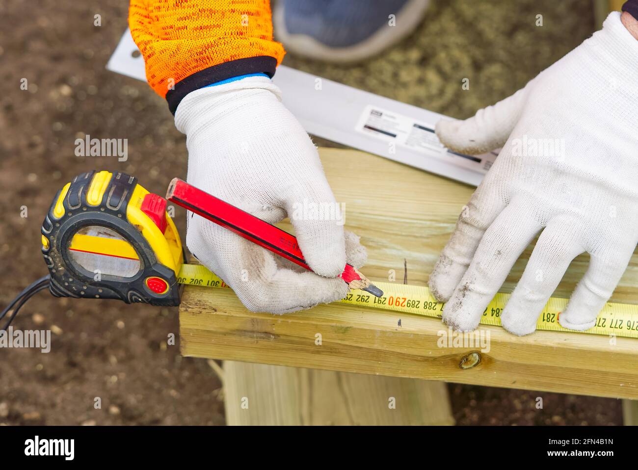 diy Carpenter marks a piece of wood. carpenter's hands in white gloves ...