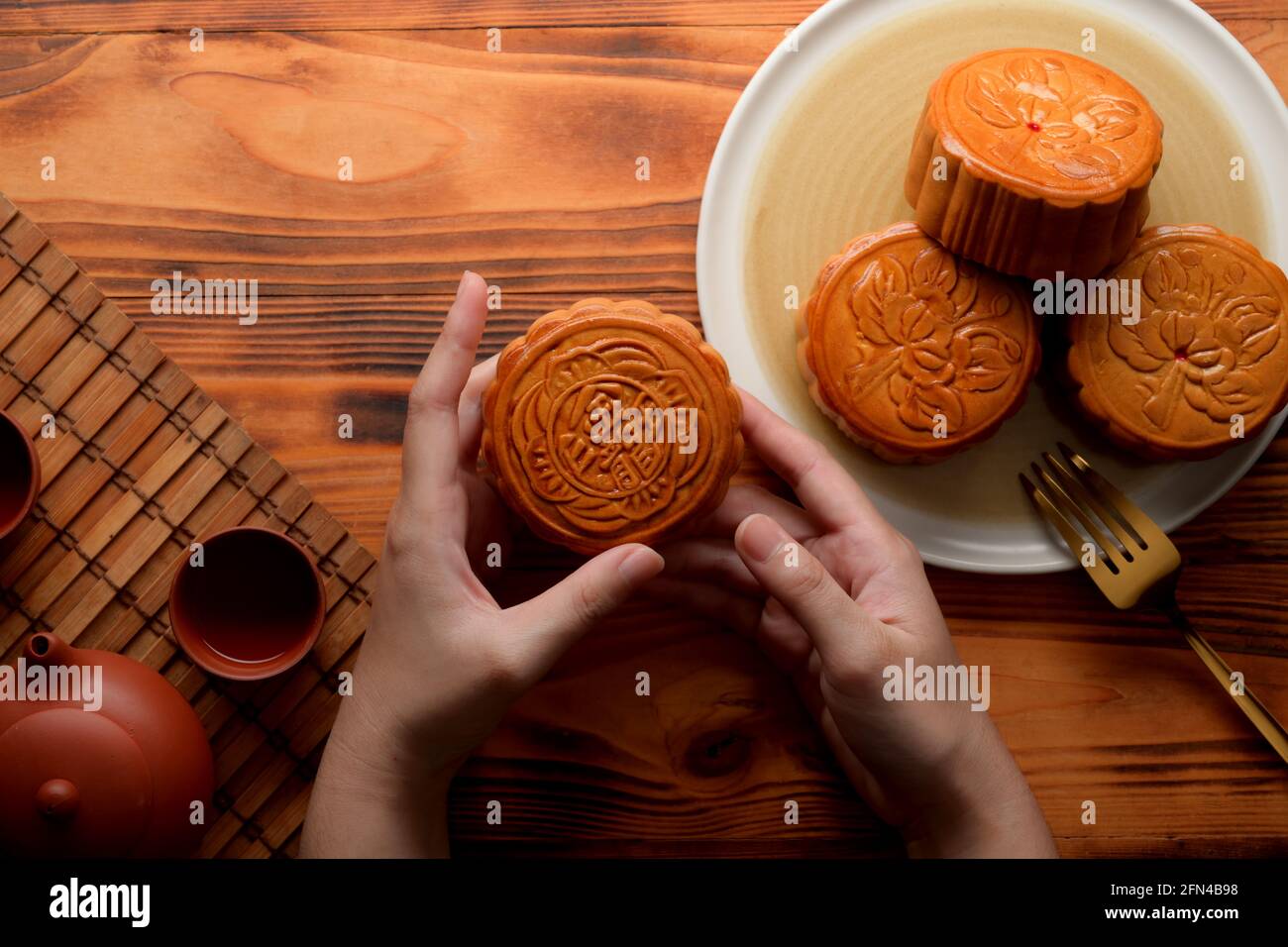 Overhead shot of female hands holding traditional moon cakes on rustic ...