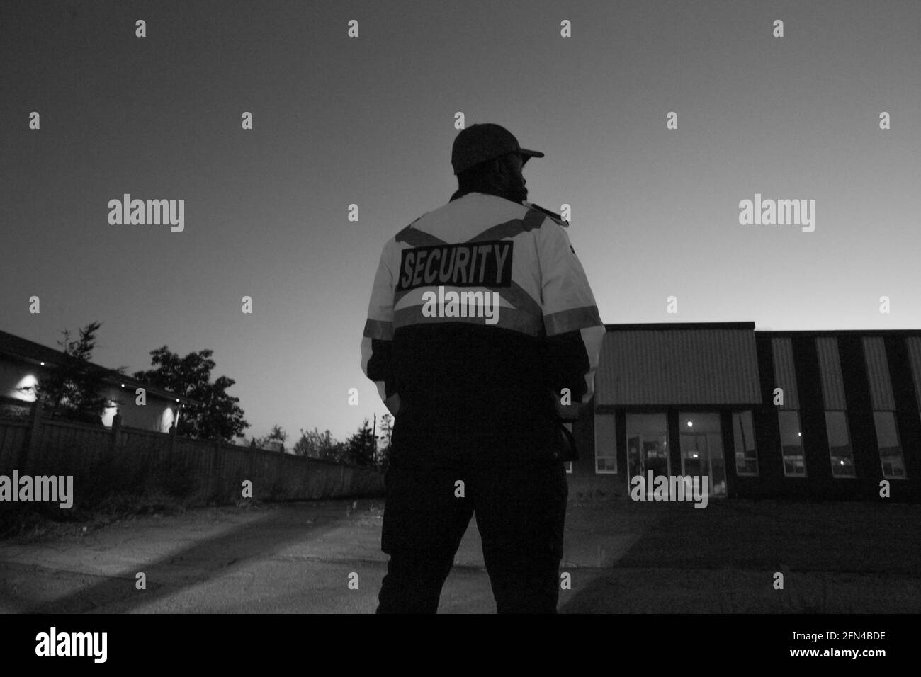 A rear view of a security guard looking down the street and sunset ...