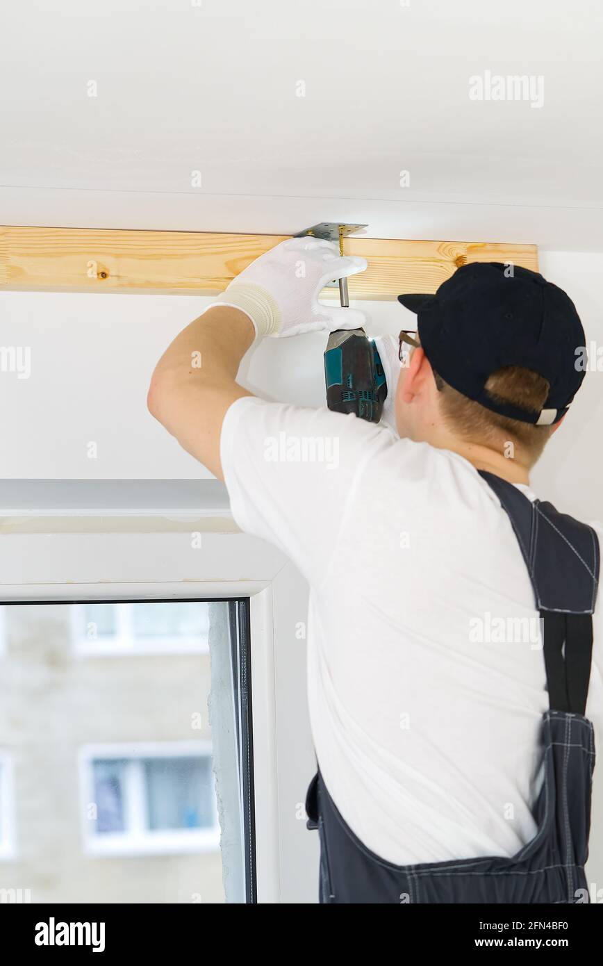 the master screws the metal corner to the concrete ceiling using a ...