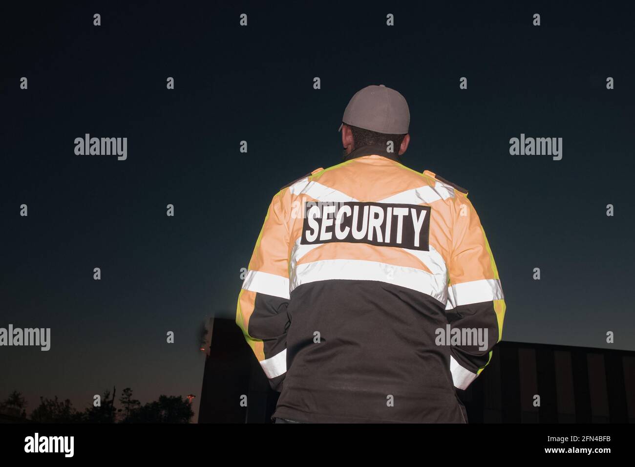 A rear view of a security guard looking down the street and sunset ...