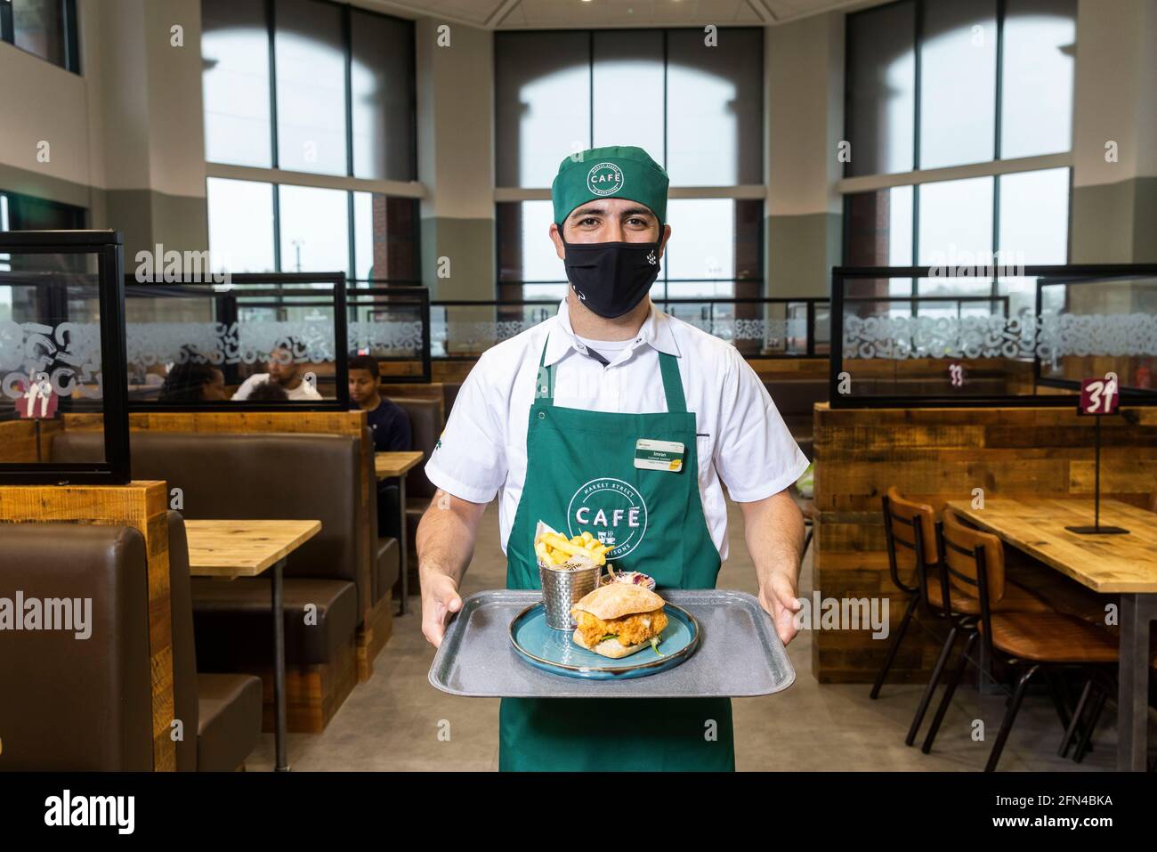 EDITORIAL USE ONLY Customer Assistant Imran Watson serves food at the ...
