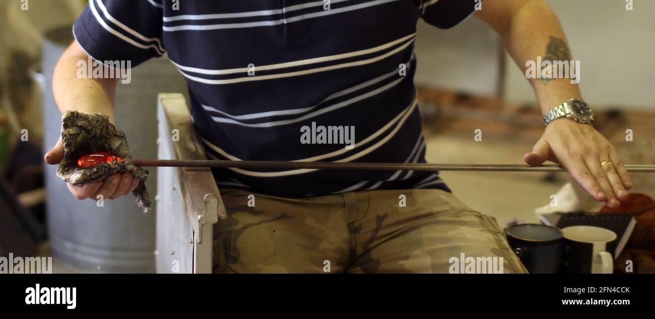 Hands of glassmaker creating glass sculptures. Factory work and crafts ...