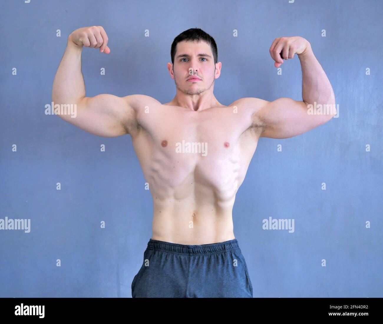 Very muscular man poses showing his muscles. Big arms, pecs and abs ...