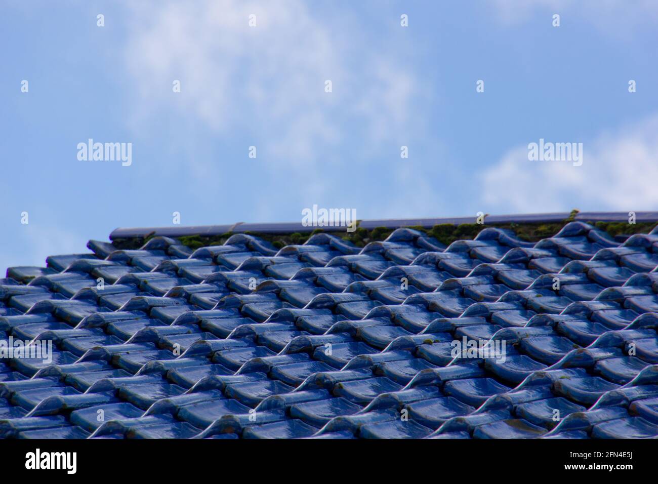 Close-up shot of a glazed blue tiled roof with a blue sky in the ...