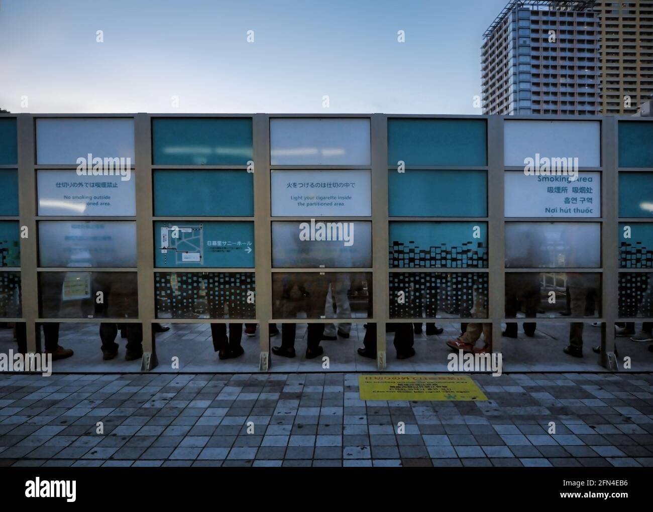 Smoking area in Tokyo. People smoking behind a barrier that creates a ...