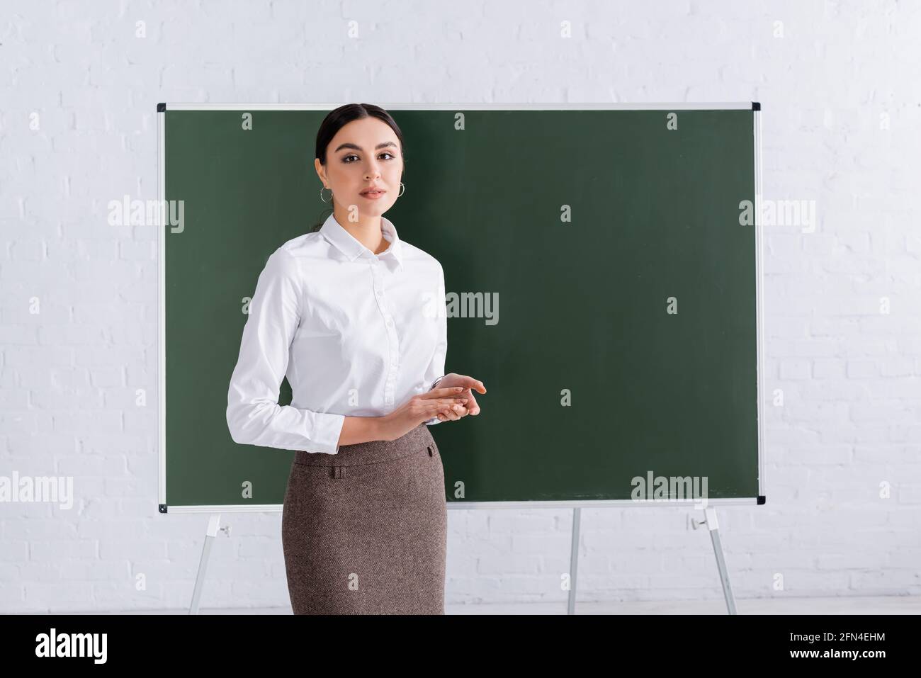 Teacher standing near chalkboard in classroom Stock Photo - Alamy