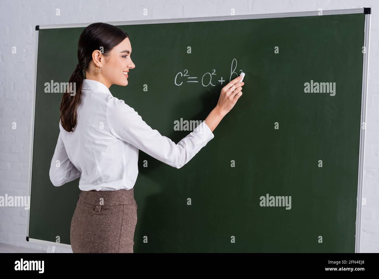 Smiling teacher writing mathematic equation on chalkboard Stock Photo ...