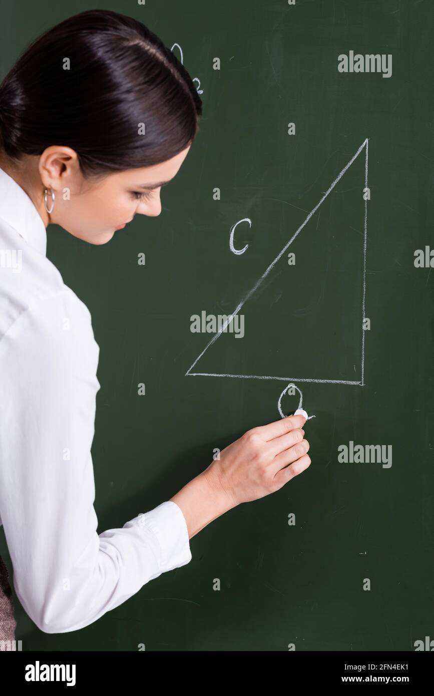 Teacher writing triangle on chalkboard in classroom Stock Photo - Alamy