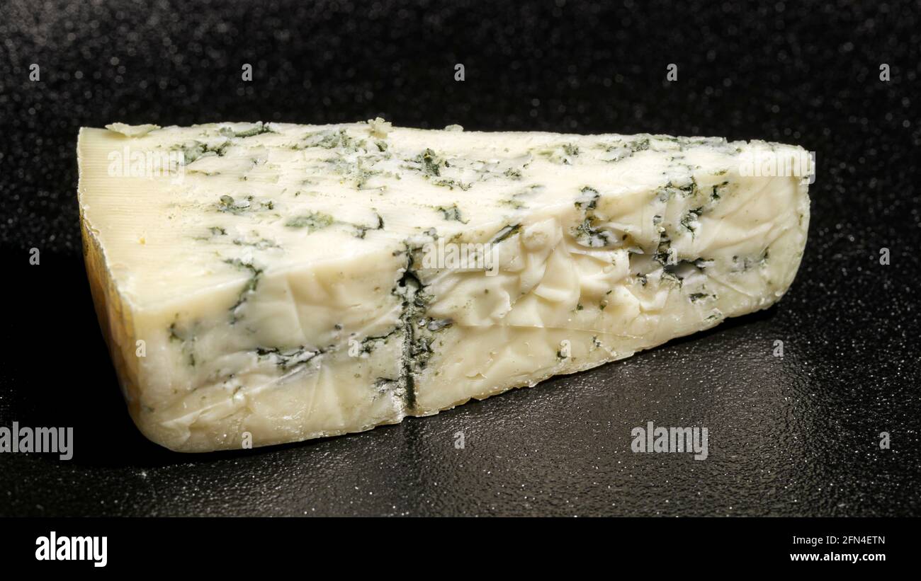 A piece of blue mold cheese on a black background Stock Photo - Alamy