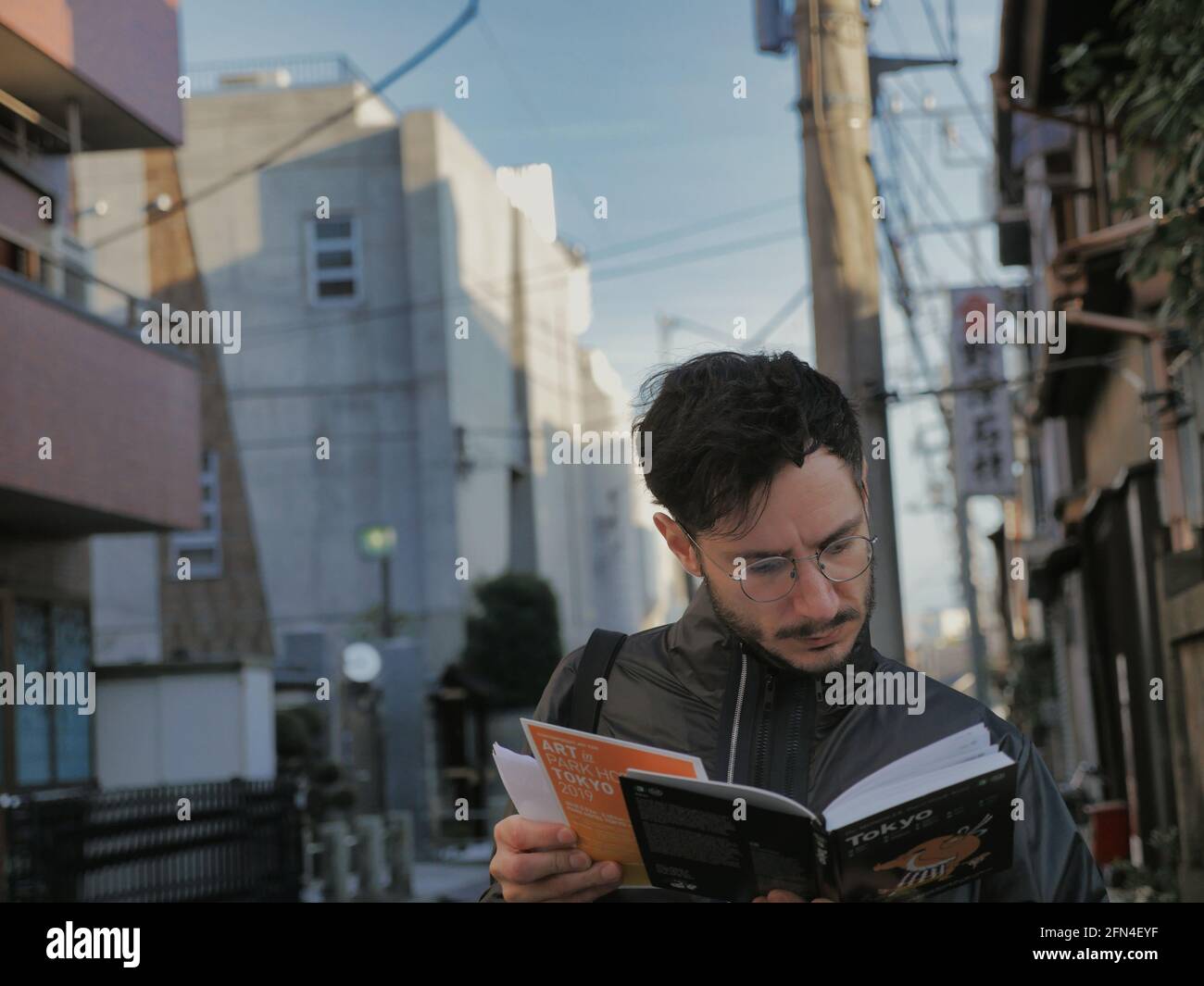 A tourist in japan reads a travel guidebook. Young tourist with glasses ...