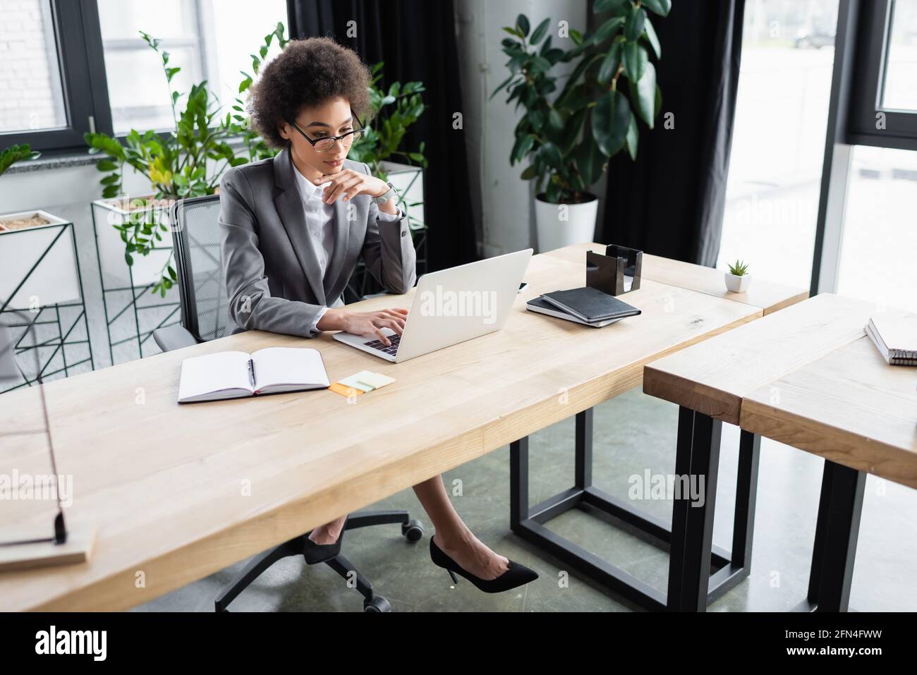 African american businesswoman using laptop near notebooks and sticky ... African american businesswoman using laptop near notebooks and sticky ...
