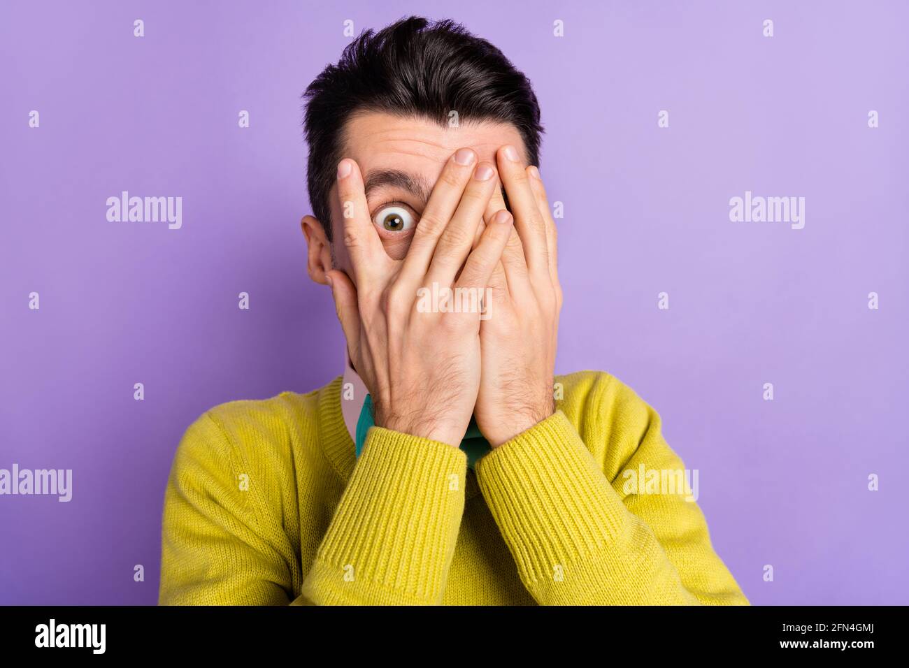 Portrait of brunet scared guy cover face wear yellow sweater isolated ...