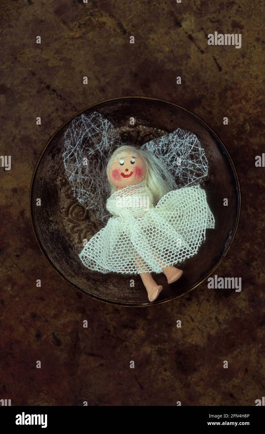Model of fairy with cheeky face and gauze dress lying in brass dish ...