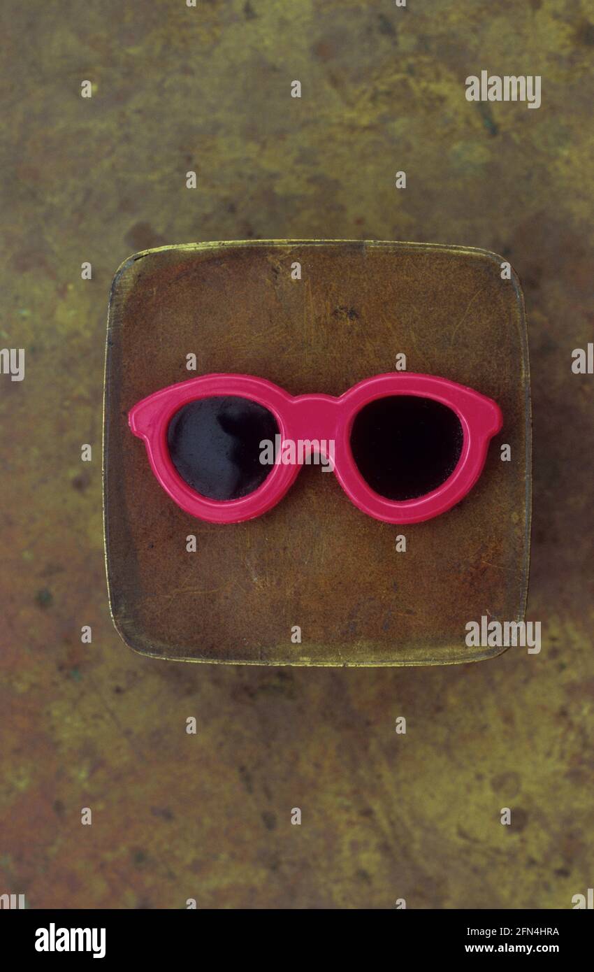 Model of pink framed sunglasses on tarnished brass box Stock Photo - Alamy