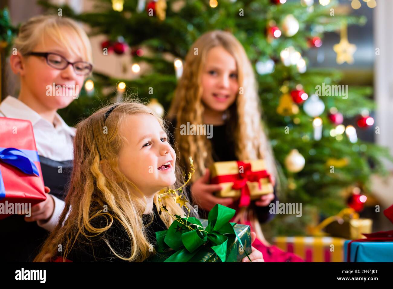Children with Christmas gift on Christmas day in family home under tree ...