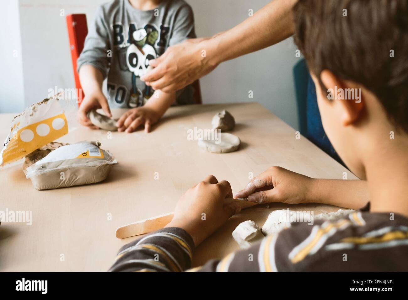 child playing with clay at home during quarantine. focused boy creating ...