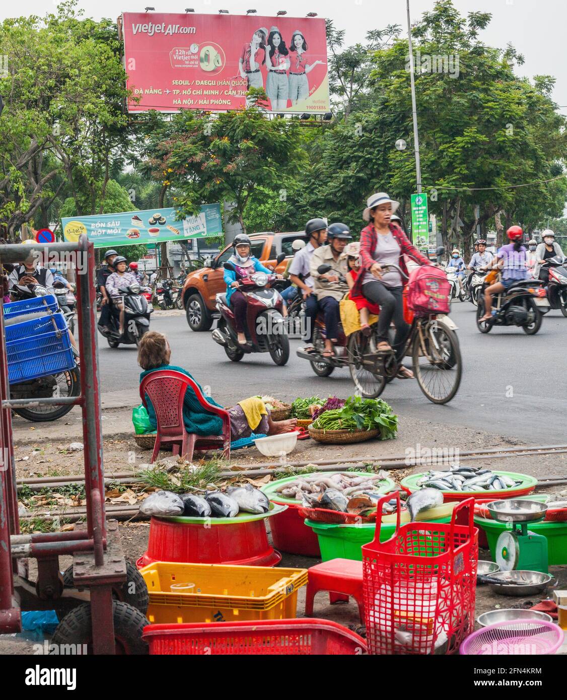 Roadside vendor selling fresh fish and vegetables as busy traffic ...