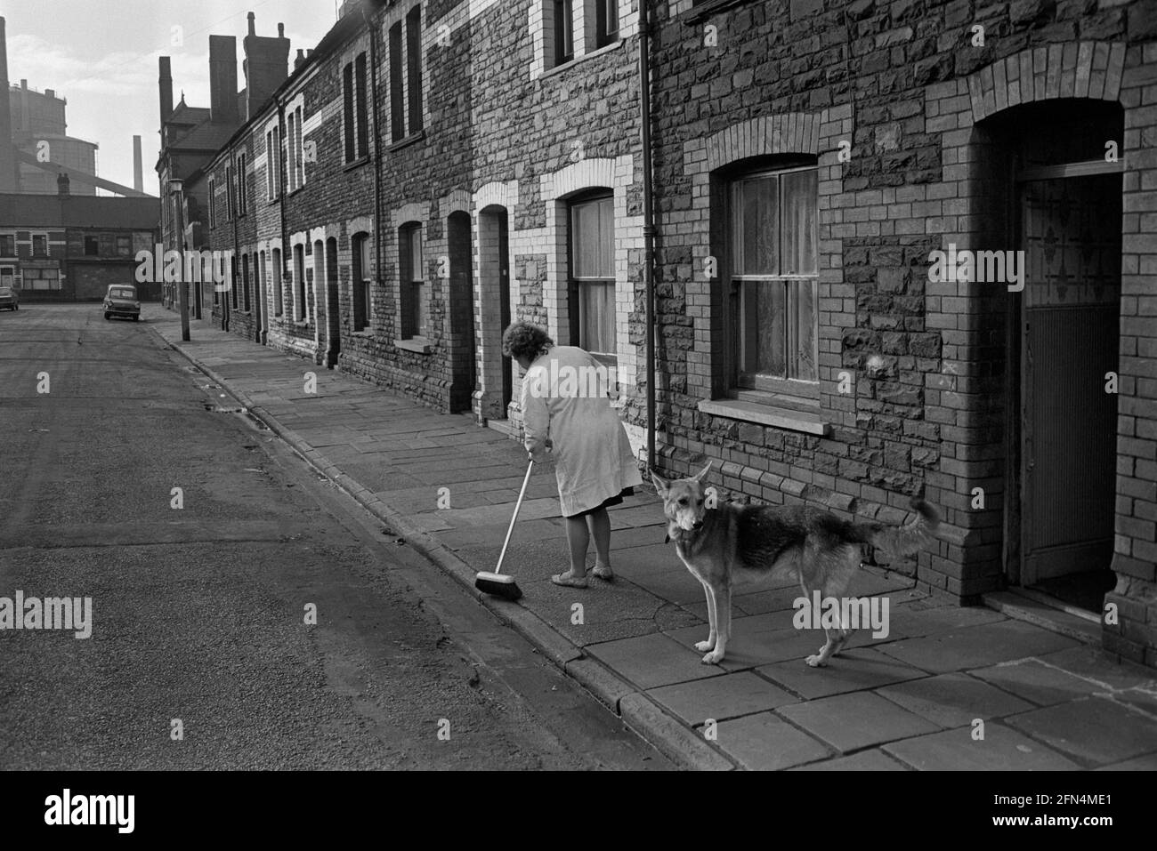A woman sweeping the street in front of her house in Splott, Cardiff ...