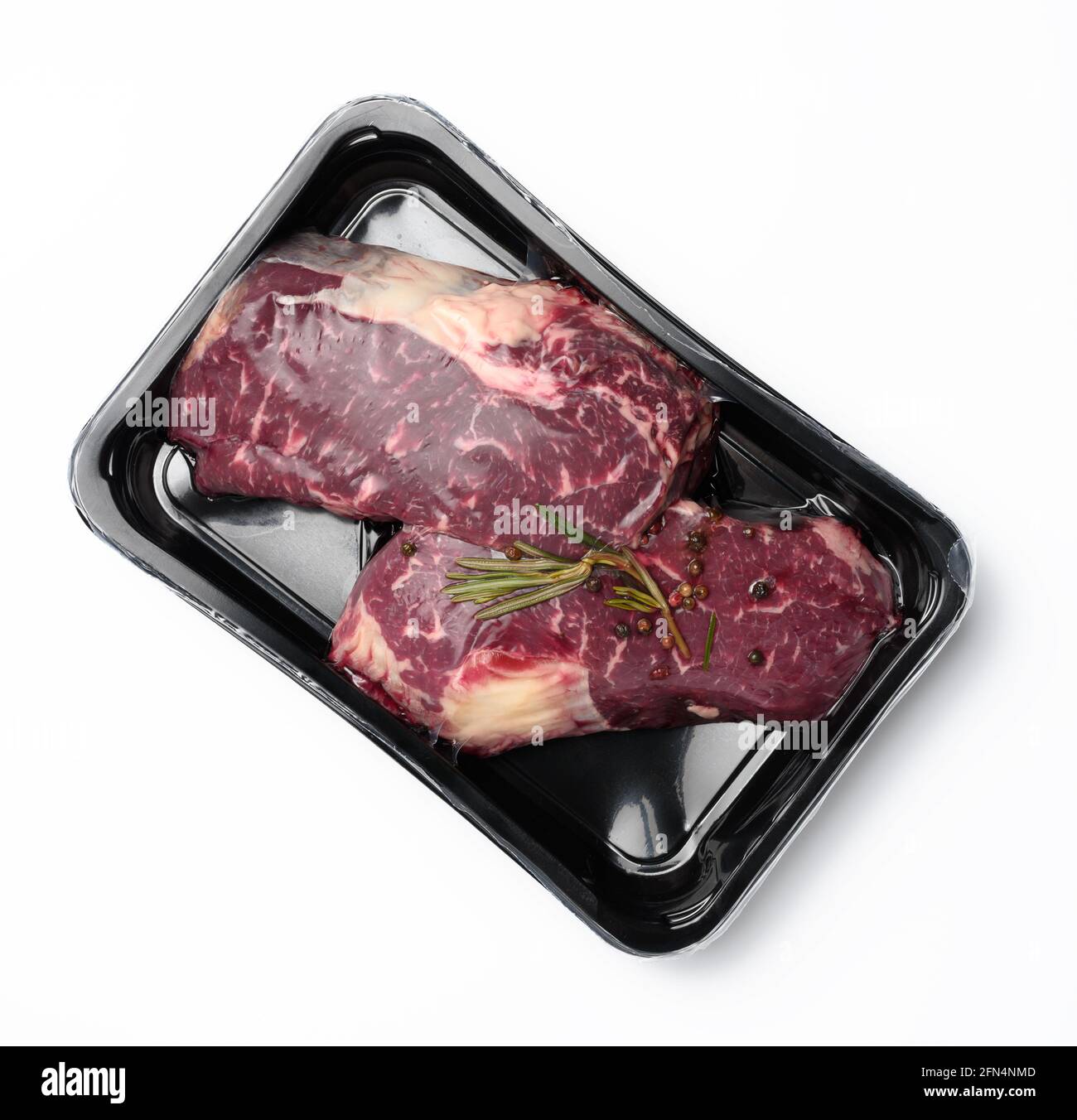 two raw beef steaks in a plastic container with spices and vacuumized ...