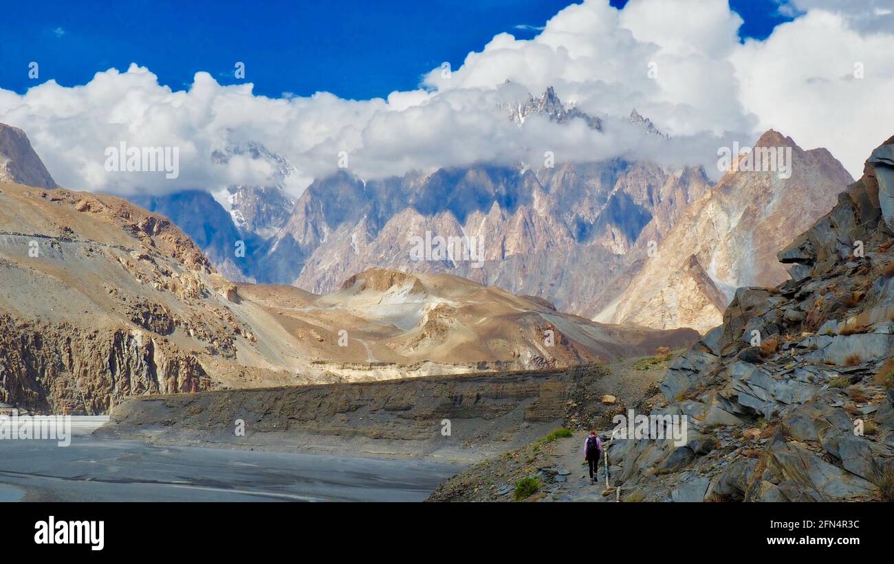 Landscape of high rocky mountains and a female hiker climbing up a ...