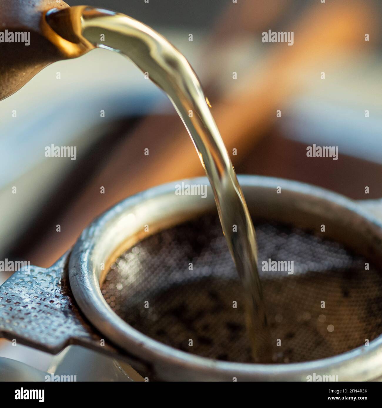 A stream of tea from the spout of the clay kettle flows into the tea ...