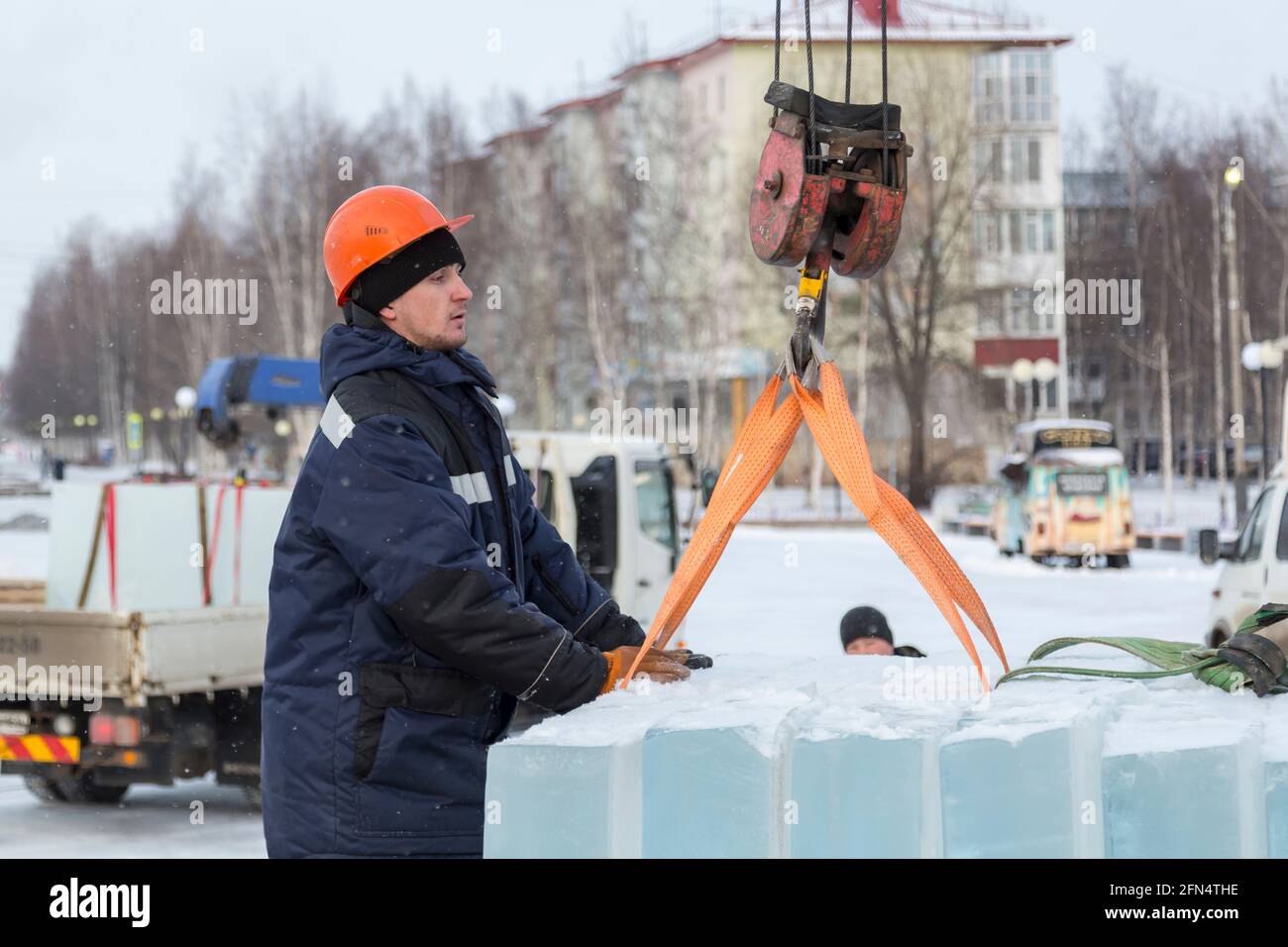Portrait of a slinger assembler in an orange helmet unloading ice slabs ...