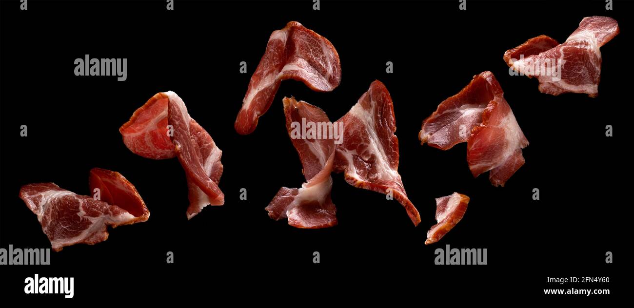 Falling sliced bacon isolated on black background Stock Photo - Alamy
