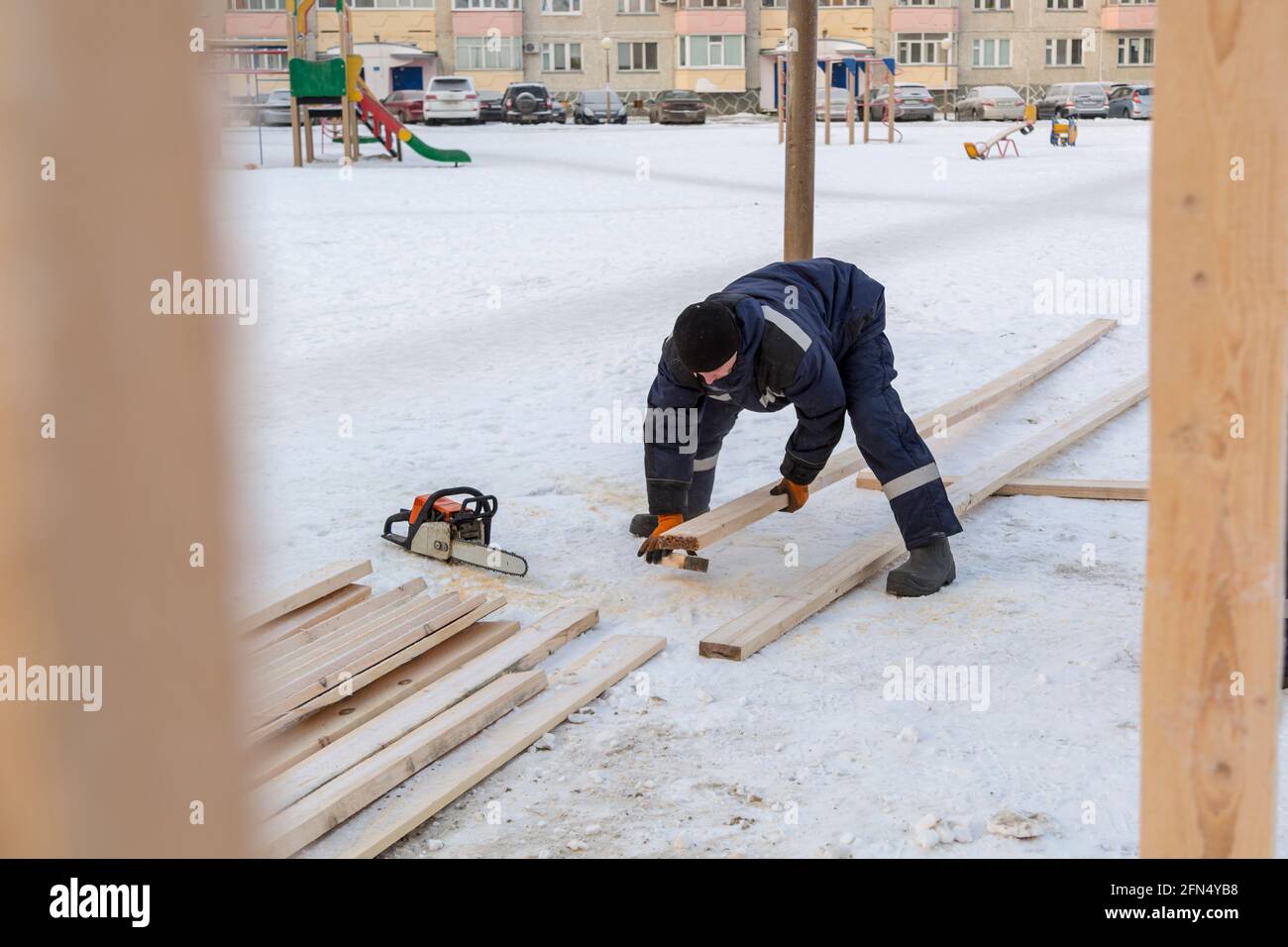 An installer in a blue jacket mounts the frame of a slide made of ...