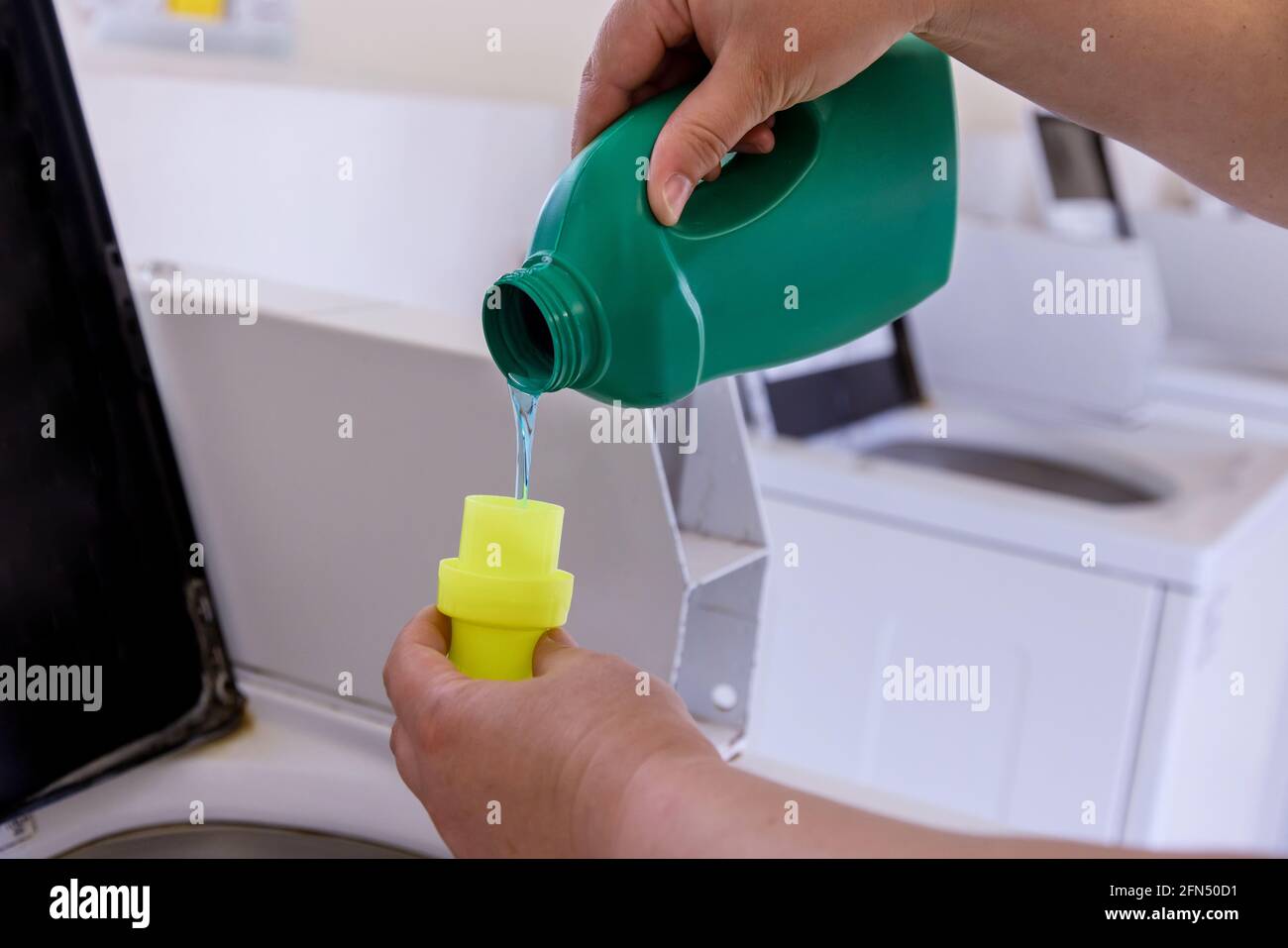 Woman pouring washing powder into the washing machine tank with laundry ...