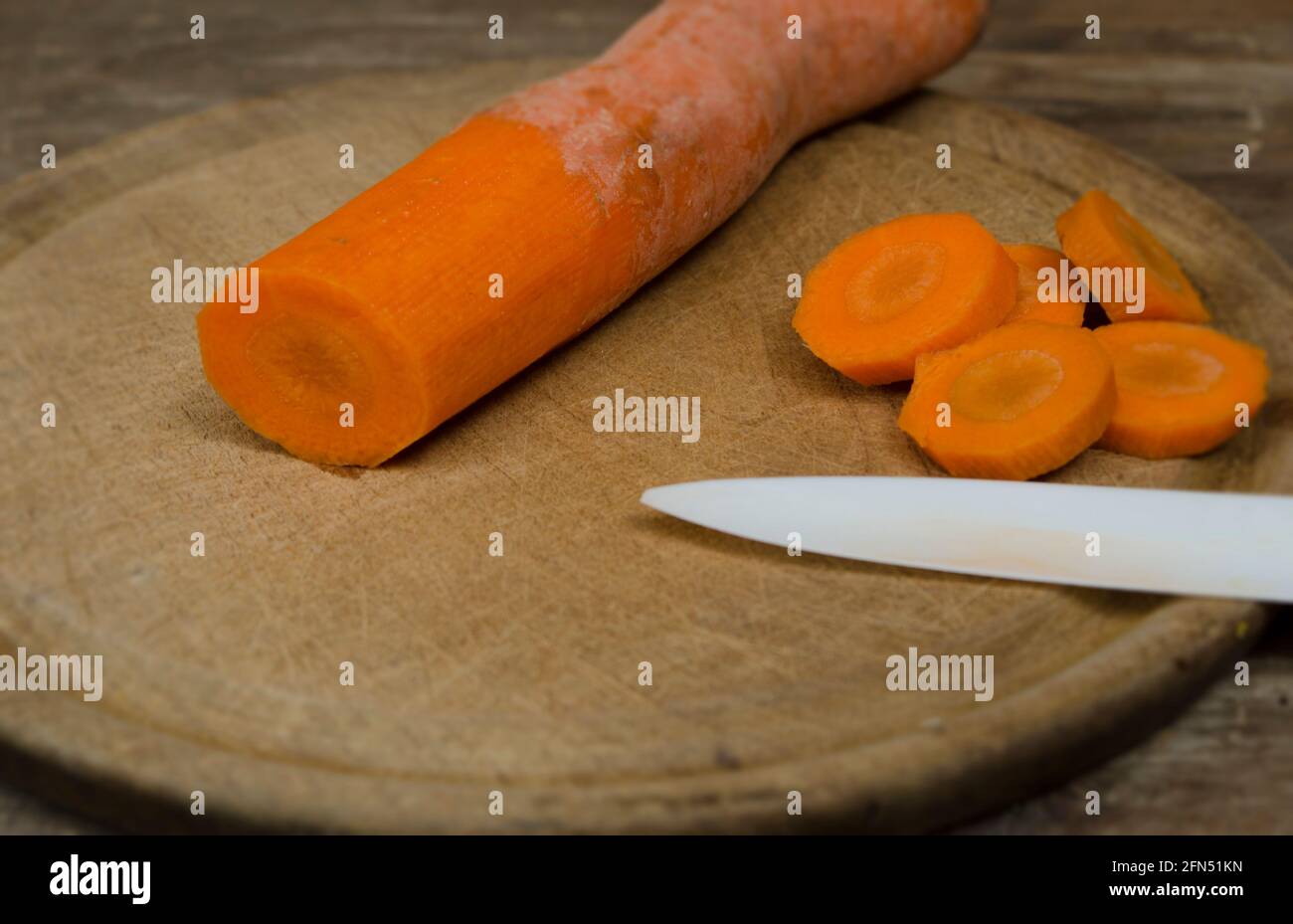 cut carrot, on plate and wooden board with ceramic knife for natural ...