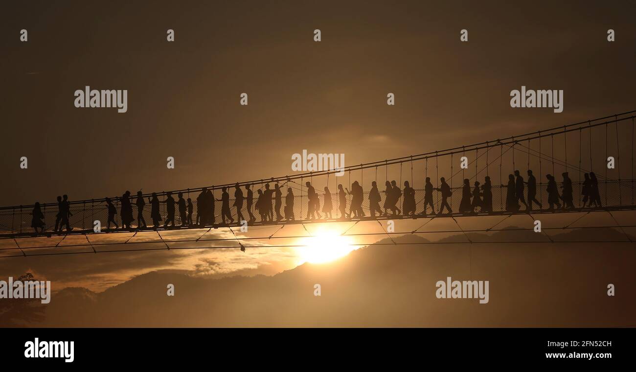 People cross a suspension bridge to go for offering prayers at a temple ...