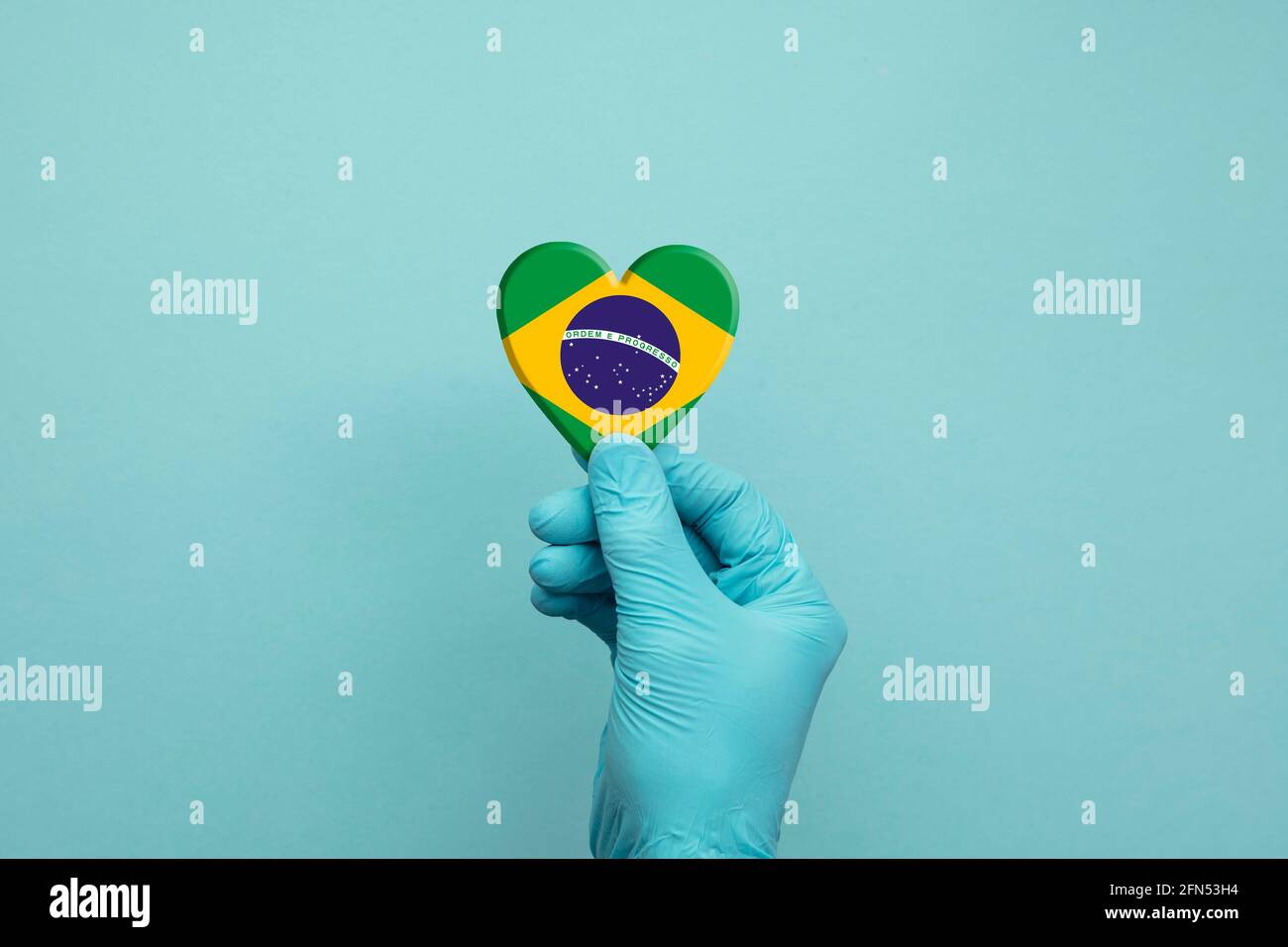 Hands wearing protective surgical gloves holding Brazil flag heart ...
