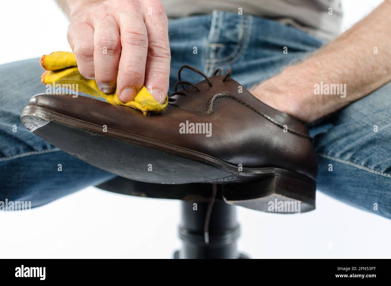 Shoe shiner shining a brown shoe with a yellow rag Stock Photo - Alamy