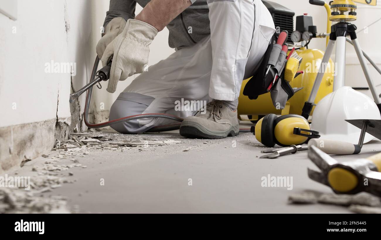 house renovation concept, construction worker breaks the old plaster of ...