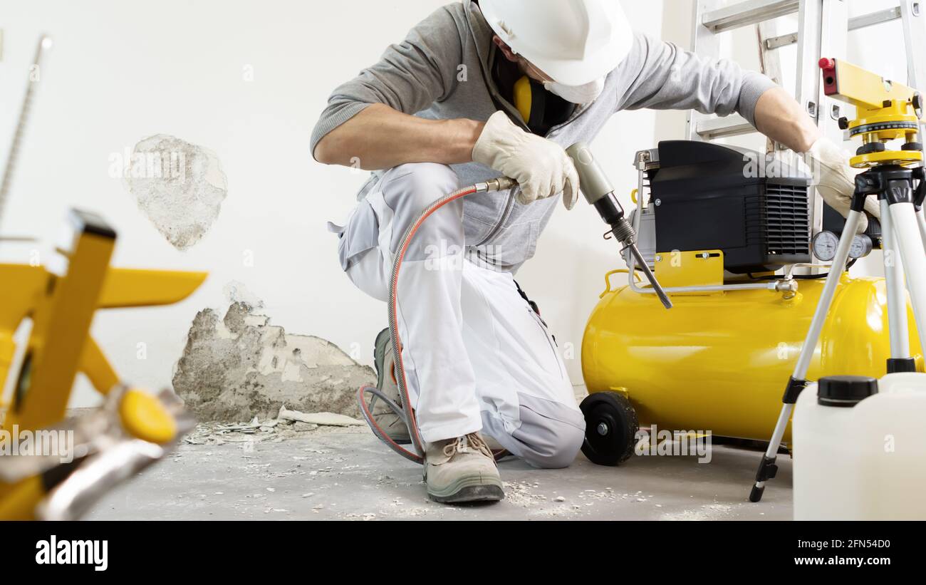 house renovation concept, construction worker breaks the old plaster of ...