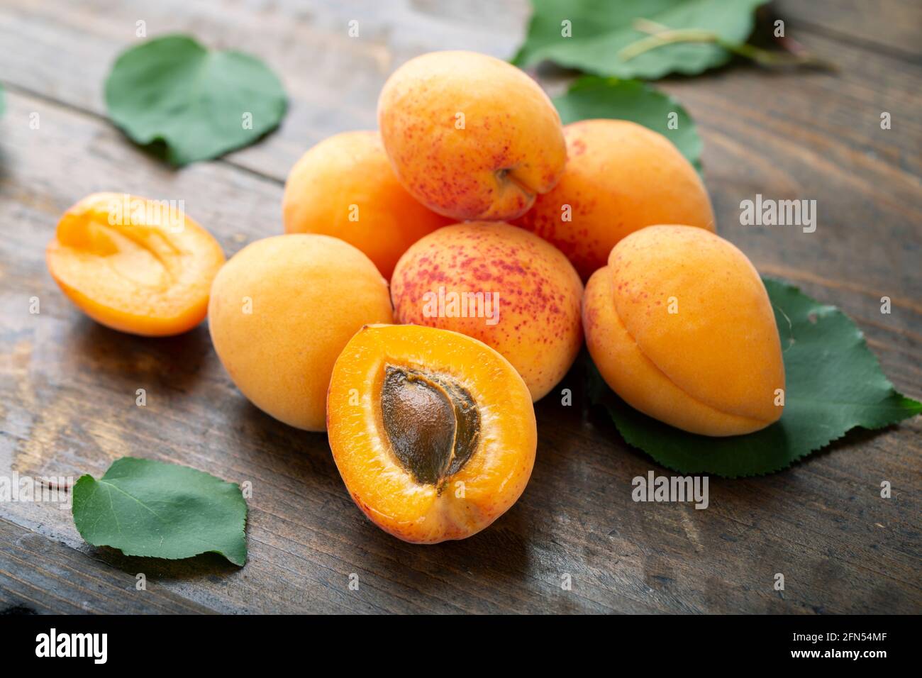 ripe apricots on a wooden background with green leaves. fresh farm ...
