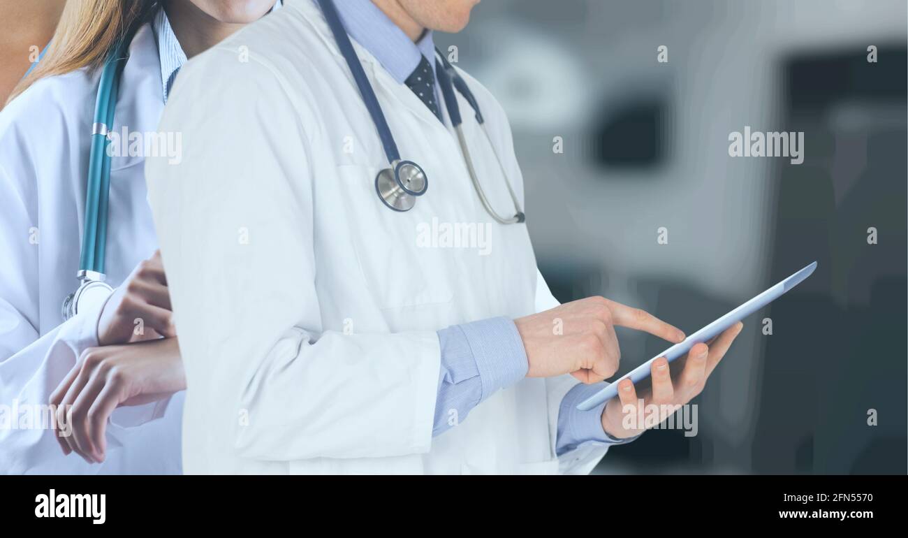 Mid section of male and female doctor using electronic devices against ...