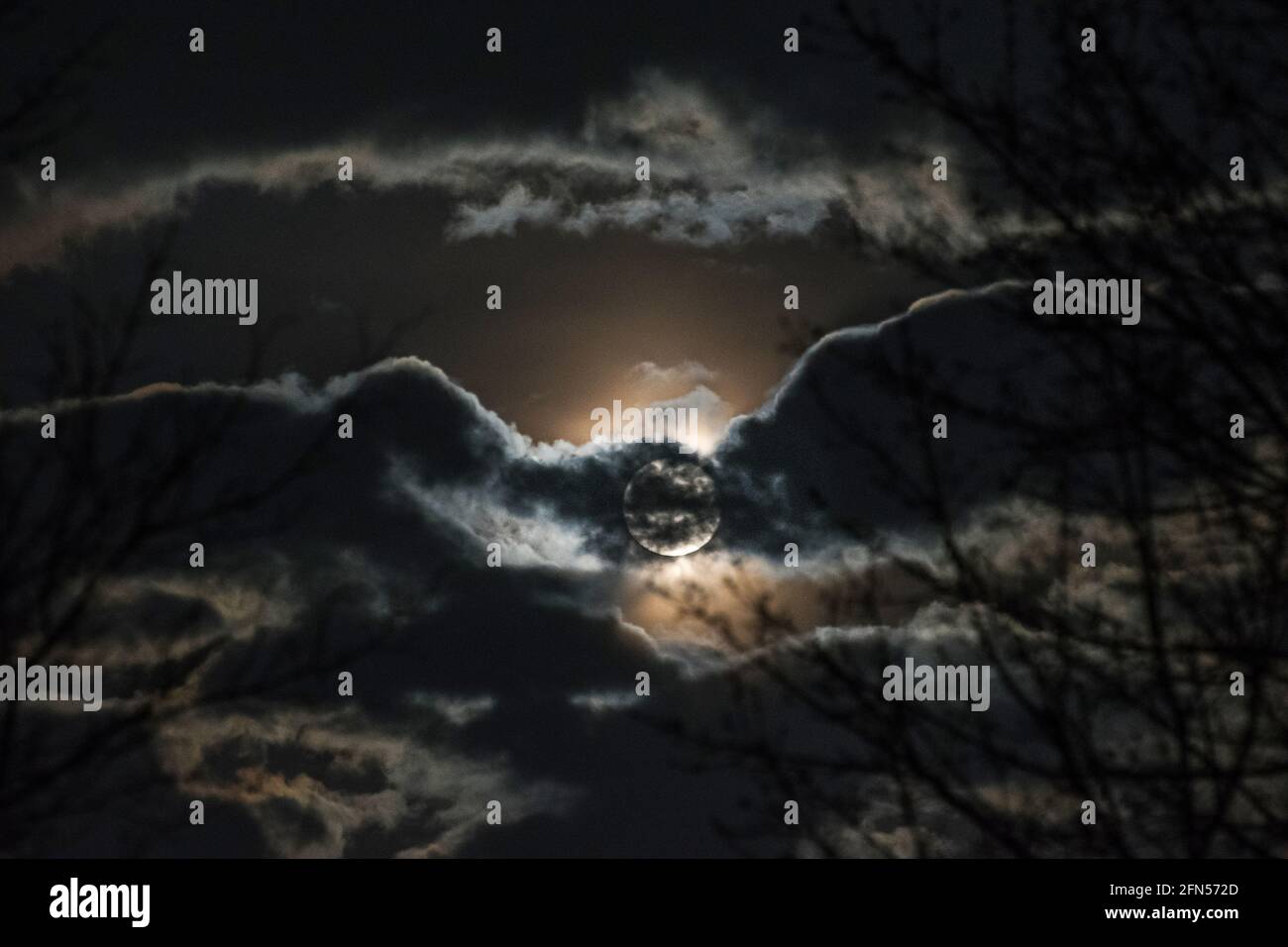 a full moon behind clouds Stock Photo - Alamy
